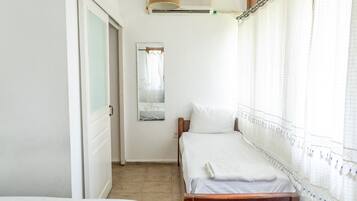 Quarto com cama, espelho e janela com cortinas.