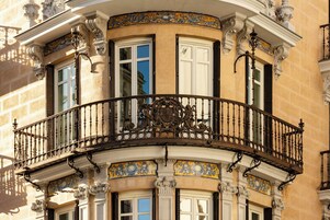 Um edifício de esquina com varandas ornamentadas, azulejos decorativos e elementos arquitetônicos clássicos.