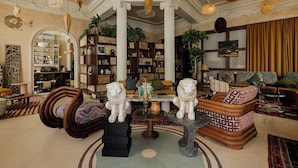 Uma sala de estar espaçosa com lareira, sofás de couro, mesa de centro e uma grande estante repleta de livros e objetos decorativos.