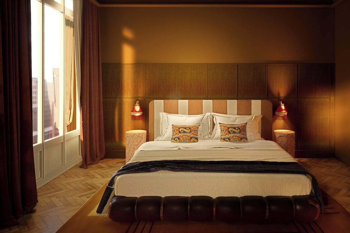 Um quarto com uma cama grande, duas luminárias de cabeceira, uma janela com cortinas e piso de madeira.