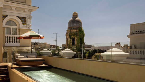 Uma área de piscina no terraço, com vista desobstruída para um edifício histórico com cúpula ao fundo.