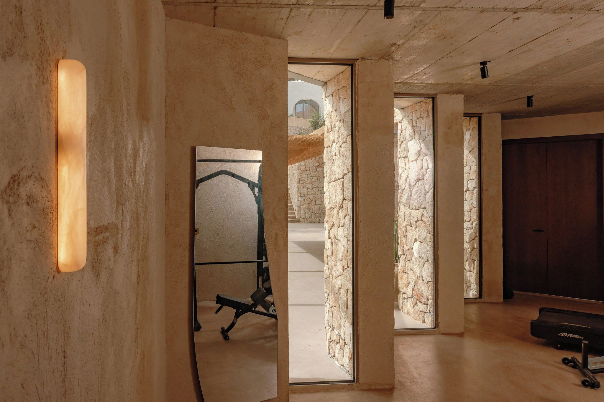 Um quarto amplo com uma janela grande, um banco e uma parede de pedra.