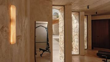 Um quarto amplo com uma janela grande, um banco e uma parede de pedra.