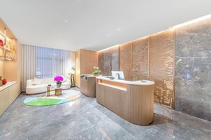 Uma área de recepção moderna, com balcão, espaço para sentar e painéis decorativos na parede.
