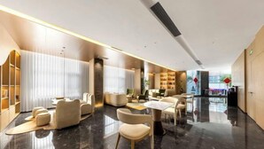 Um hall de hotel moderno com piso de mármore polido, mobiliário contemporâneo e uma grande área de estar.