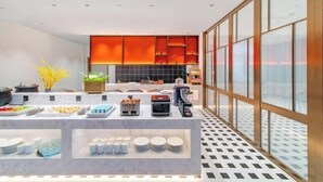 Uma cozinha moderna com bancada de mármore, cafeteira e vista através de grandes janelas.