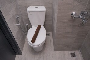 Casa de banho moderna com sanita branca, área de duche e porta-toalhas.