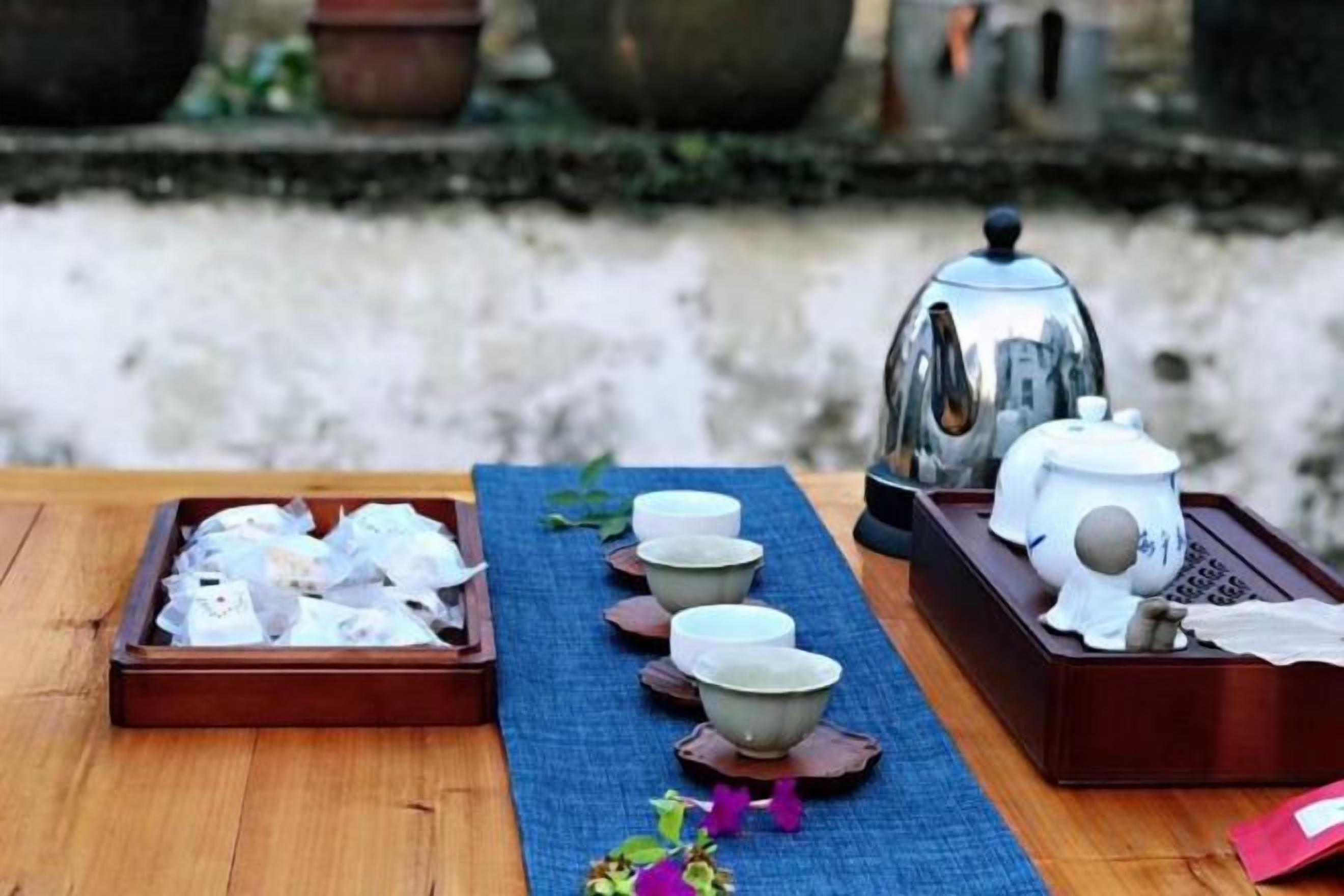 Uma mesa com jogos de chá e xícaras, um bule e uma bandeja com sachês de chá.