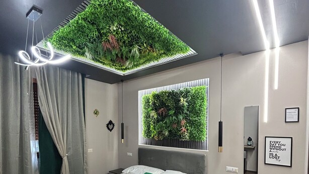 Quarto moderno com cama, parede verde e jardim vertical.