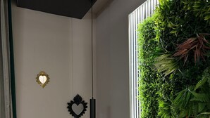Quarto moderno com parede cinza, luminária pendente preta, decoração em formato de coração e jardim vertical.