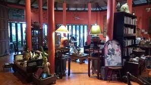 Um quarto amplo com pé direito alto, grandes janelas e diversos móveis, incluindo um sofá, cadeiras e uma mesa de centro.