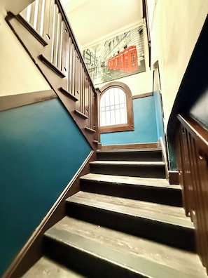 Uma escadaria com corrimão, uma janela com grades e uma parede com um mural.