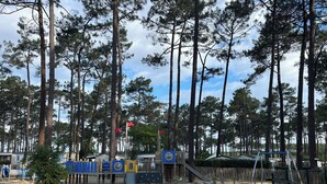 Um parquinho com areia, um banco de madeira e um escorregador.
