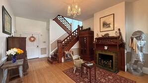 Uma sala de estar ampla com escada de madeira, lareira e um candelabro.