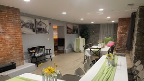 Uma sala de jantar com mesas postas para refeição, com toalhas de mesa verdes e vasos brancos com flores.