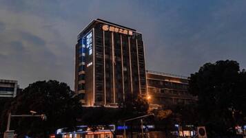 Edifício de vários andares com uma placa vertical chamativa na fachada, possivelmente indicando um hotel ou estabelecimento comercial.