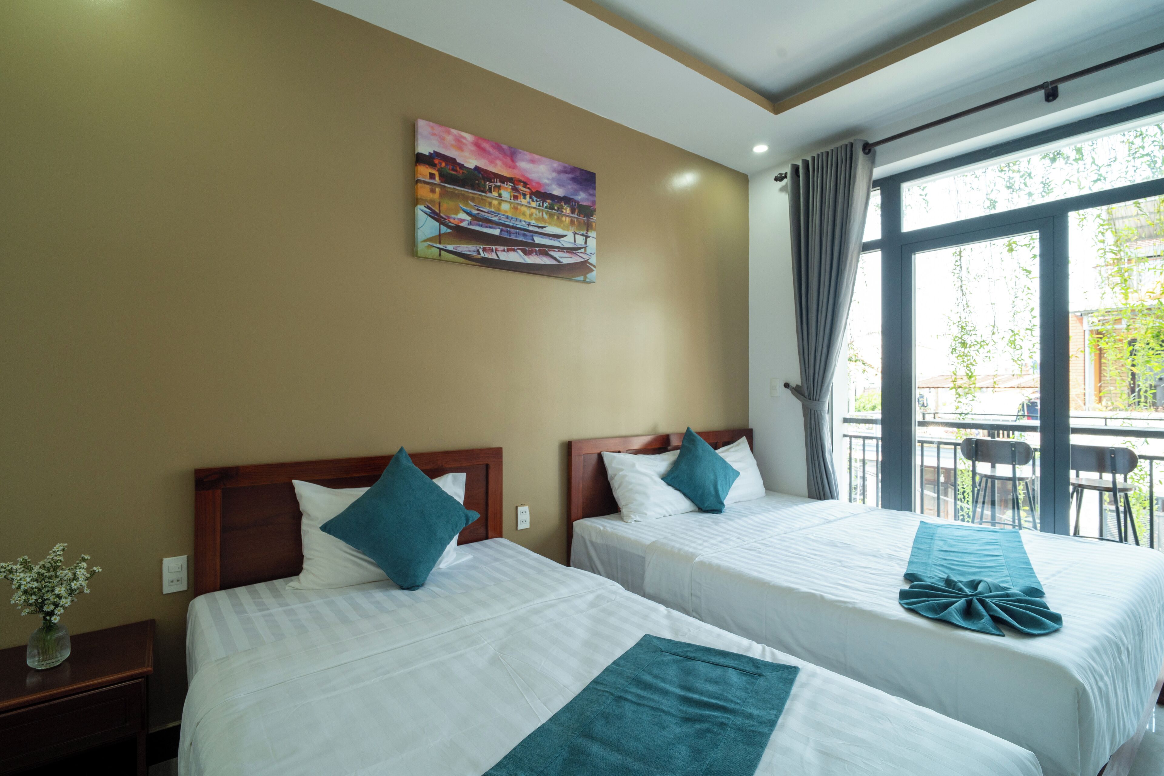 Quarto de hotel com duas camas, um quadro na parede e vista para o exterior.
