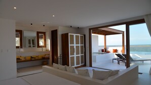 Quarto moderno com uma cama grande, um closet espaçoso e uma varanda com vista para o oceano.