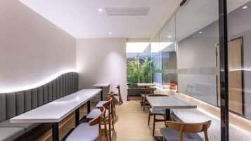 Interior moderno de restaurante com balcão extenso, área de estar e vista através de parede de vidro.