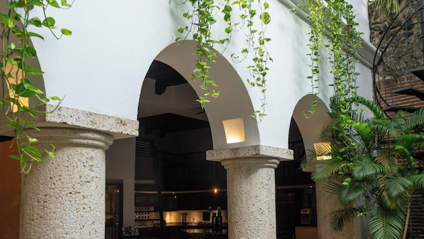 Um pátio com piscina, colunas de pedra e arcos.