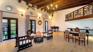 Um quarto espaçoso com teto alto, vigas de madeira, um candelabro e um piano.