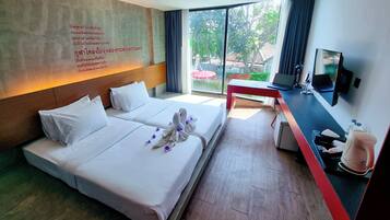 Quarto de hotel com duas camas, uma escrivaninha com um laptop, televisão e vista para o exterior.