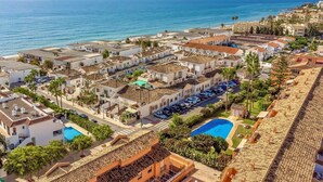 Uma área residencial costeira com vários edifícios, uma piscina e vista para o mar.