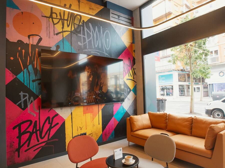Interior moderno com parede de graffiti colorida, uma grande televisão de tela plana, sofá de couro e máquina de café.