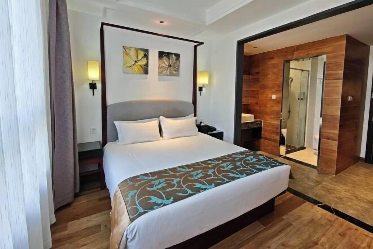 Quarto de hotel com uma cama grande, piso de madeira, um espelho e um painel de parede em madeira.