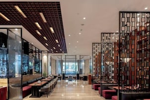 Restaurante moderno com um balcão extenso, área de estar e divisórias decorativas.