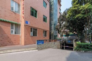 Um edifício com fachada de tijolos, uma placa azul e entrada com portão.