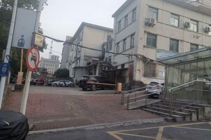 Edifício com escadaria que leva a uma entrada, placa de proibido estacionar e área coberta com degraus.