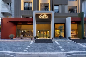 Entrada de hotel com design moderno, fachada de vidro e ambiente acolhedor.