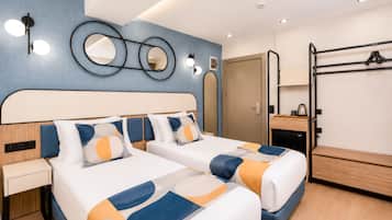 Quarto de hotel com duas camas, uma mesa de cabeceira, escrivaninha, espelho e guarda-roupa.