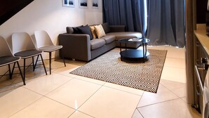 Uma sala de estar moderna com um sofá, cadeiras, uma mesa de centro e um tapete estampado.