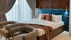 Um quarto moderno com uma cama grande, cabeceira estofada e parede com padrão geométrico.