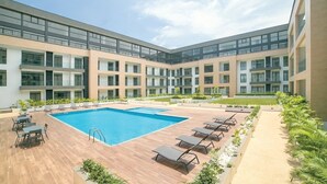 Um edifício moderno com uma piscina central, rodeada por espreguiçadeiras e mesas.