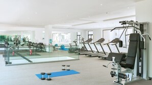Academia moderna com equipamentos de cardio, pesos livres e um espelho grande.