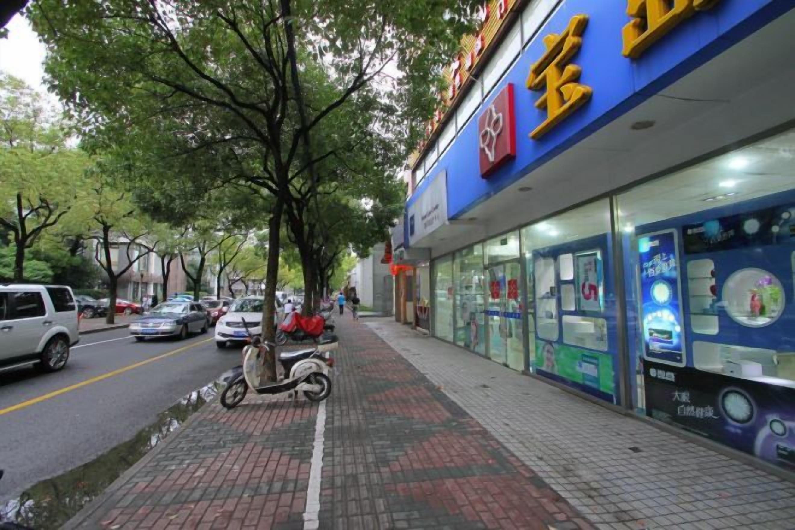 Vista da rua com um prédio que tem marquise azul e uma placa com caracteres amarelos.