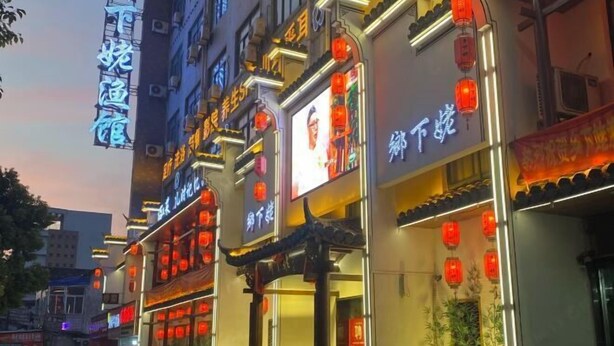 Fachada de hotel com sinalização iluminada, elementos arquitetônicos tradicionais e entrada visível.