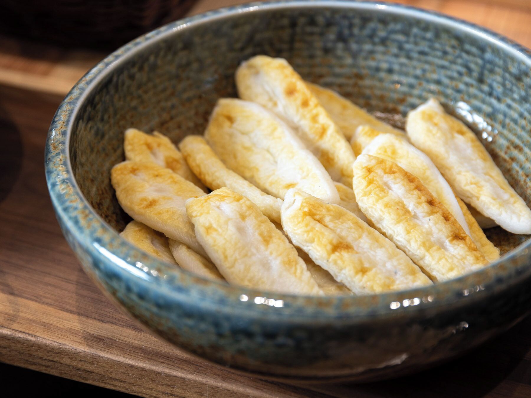 Uma tigela com fatias de banana sobre uma superfície de madeira.