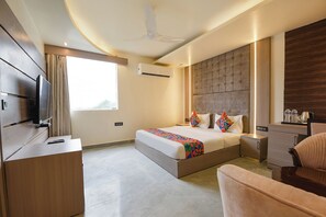 Quarto de hotel moderno com uma cama grande, televisão, escrivaninha e cadeira.