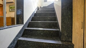 Uma escadaria com degraus de granito escuro que levam a um patamar.