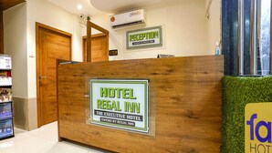 Balcão de recepção com uma placa indicando Hotel Regal Inn, área de recepção e balcão de check-out.