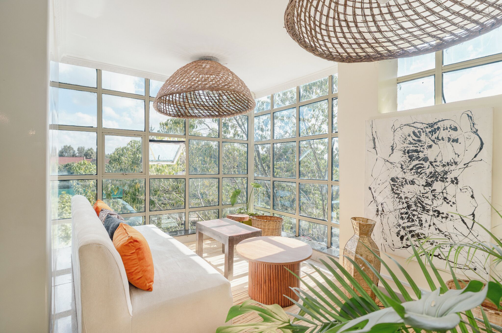 Um quarto com grandes janelas, um sofá, uma mesa e um lustre.