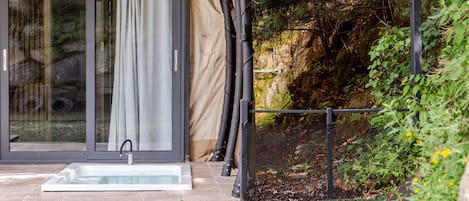 Uma área externa moderna com porta de vidro, uma pequena piscina e um jardim com cerca.