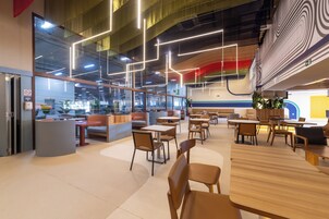 Um café moderno com diversas opções de assento, incluindo mesas, cadeiras e um balcão. Cozinha visível ao fundo.