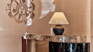 Balcão de recepção com tampo de mármore, um relógio de parede e uma luminária.