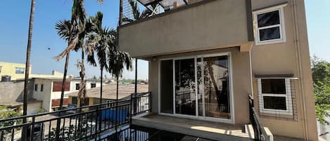 Um edifício moderno de dois andares com varanda, janelas amplas e telhado plano.