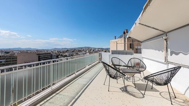 Uma varanda com mesa e cadeiras, vista para a cidade.